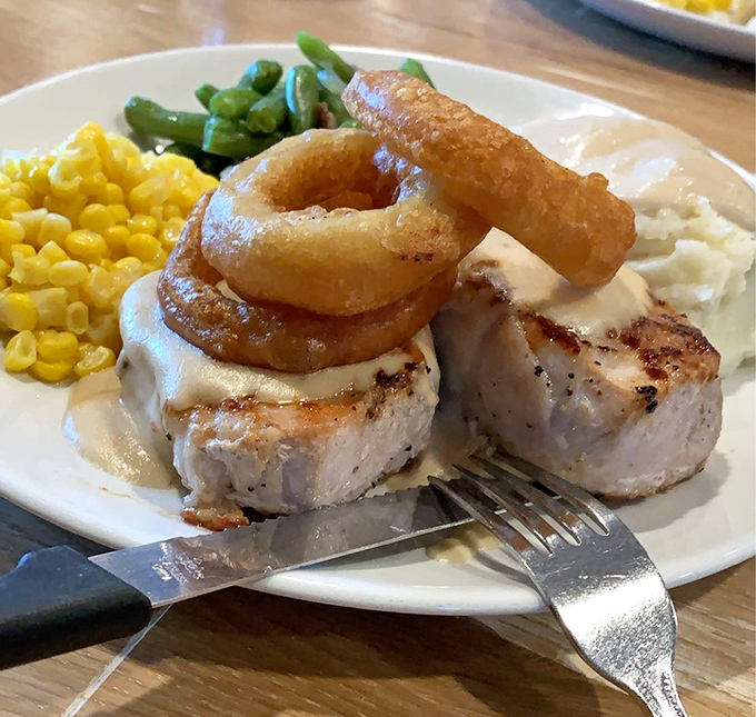 Pork chop perfection topped with crispy onion rings&mdash;proof that sometimes the simplest pleasures deliver the most profound satisfaction.