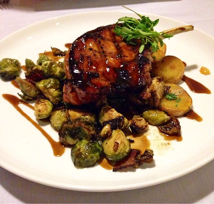 This isn't just any pork chop—it's a masterpiece of caramelization, perched atop Brussels sprouts that might convert even the most dedicated vegetable skeptics.