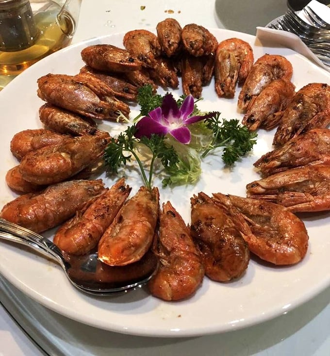 A crown of prawns arranged like they're posing for their royal portrait. That purple orchid isn't just garnish&mdash;it's announcing "this is no ordinary seafood."