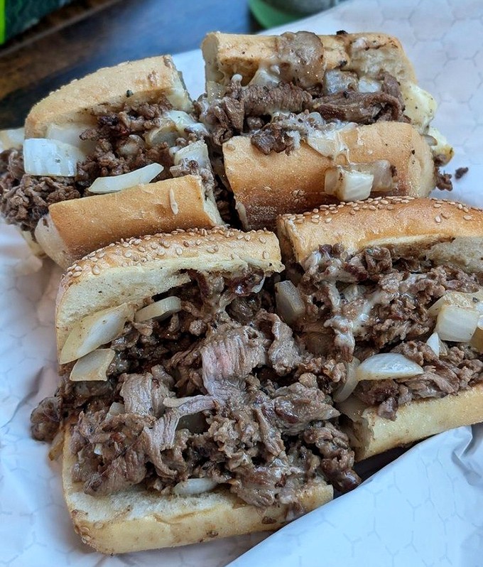 Prime rib cheesesteaks cut into quarters reveal the perfect pink interior&mdash;proof that sometimes the best things in life require both hands and extra napkins.