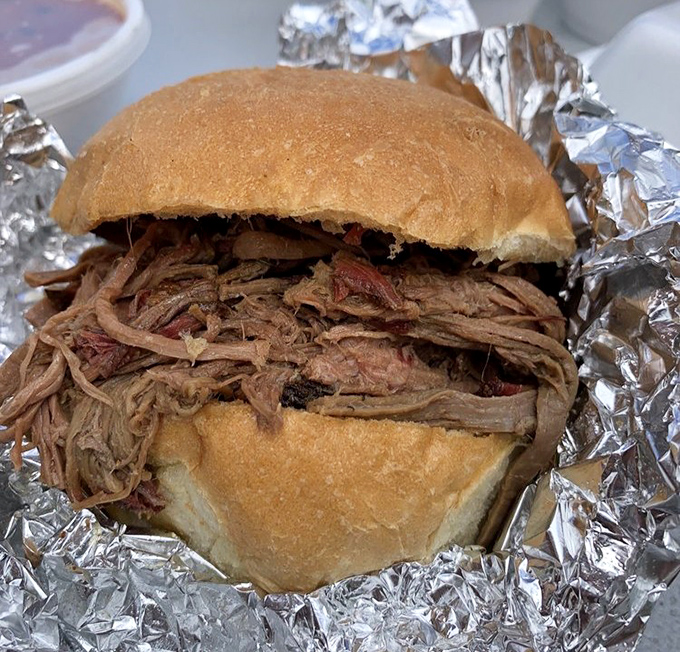 A sandwich that requires both hands and possibly a liability waiver. This pulled brisket doesn't so much sit on the bun as command it.