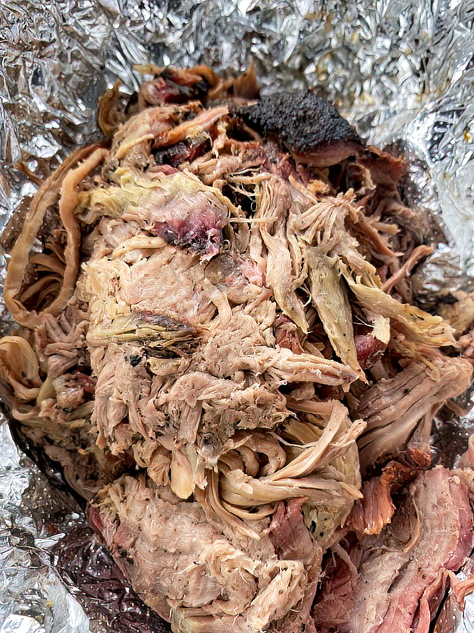 Pulled pork that surrenders at the sight of a fork. Those crispy bark bits mixed throughout are like finding extra money in your pocket.