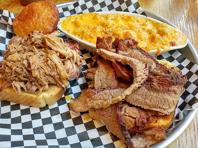 Barbecue alchemy at its finest – pulled pork and brisket sharing a plate with that famous mac and cheese. The holy trinity of comfort.