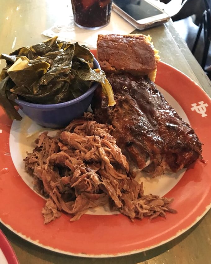 A holy trinity of Southern comfort: pulled pork with that perfect shred, collard greens cooked to silky submission, and cornbread that doesn't know the meaning of "dry."