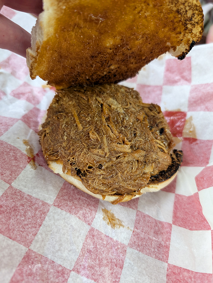 Pulled pork perfection on a classic roll. The meat's been smoking longer than most rock bands, and it shows in every tender, flavorful strand.