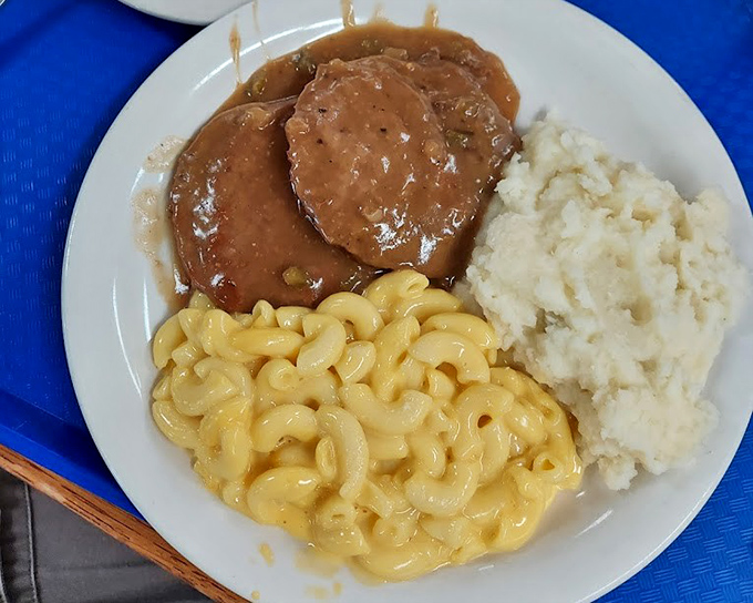 Salisbury steak swimming in gravy alongside mac and cheese that clearly never met a powdered packet in its life.