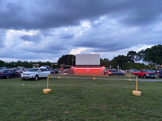 As twilight settles, the massive screen awaits its moment to shine, surrounded by vehicles instead of velvet seats.