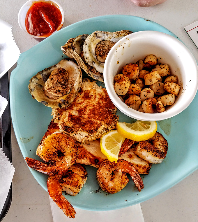 Blackened shrimp, grilled fish, and oysters share a turquoise plate like old friends at a reunion. That lemon wedge isn't just garnish—it's essential!