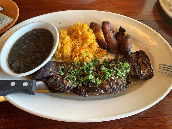 The Skirt Steak Churrasco arrives like a carnivore's dream—perfectly charred, topped with chimichurri, and accompanied by black beans that could start their own fan club.