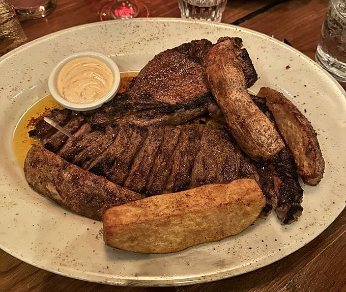 Primal and refined collide on this plate. The steak arrives with a side of golden onion rings that crunch loud enough to turn heads.