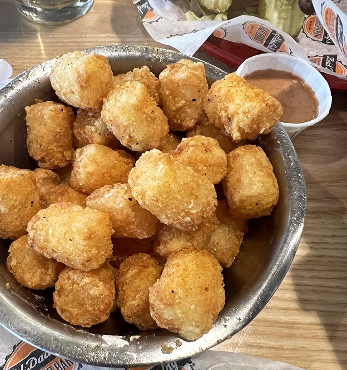 Golden-brown tater tots huddle together in their metal bowl, plotting how to steal the spotlight from the main course.