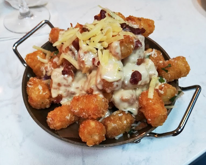 Tater tots have grown up and gone to culinary school. These golden nuggets, smothered in cheese and bacon, are what childhood dreams become.