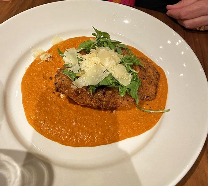 The Tavern Chicken basks in a vibrant orange Romesco sauce, topped with fresh arugula and Parmesan&mdash;comfort food dressed for a night out.
