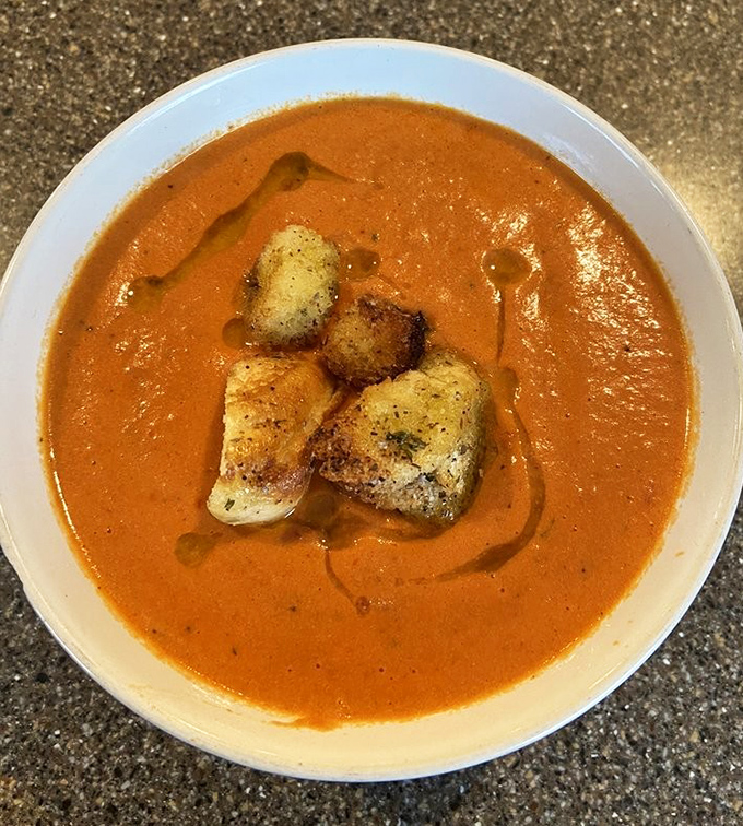 Tomato bisque elevated to art form. Those croutons aren't just floating &ndash; they're doing the backstroke in a pool of velvety perfection.