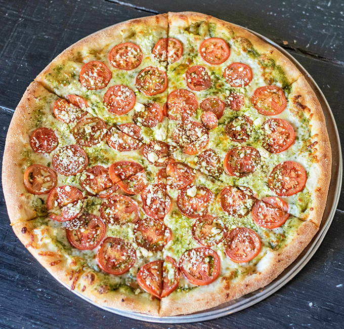 The Tomato Pesto pizza &ndash; where East Coast tradition shakes hands with California innovation. Those fresh tomatoes are practically sunbathing in basil goodness.