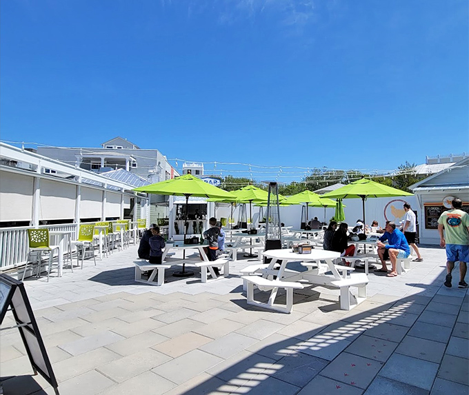 Bright umbrellas and pristine picnic tables create an inviting communal dining space where strangers become friends over shared meals and the universal language of "pass the napkins."