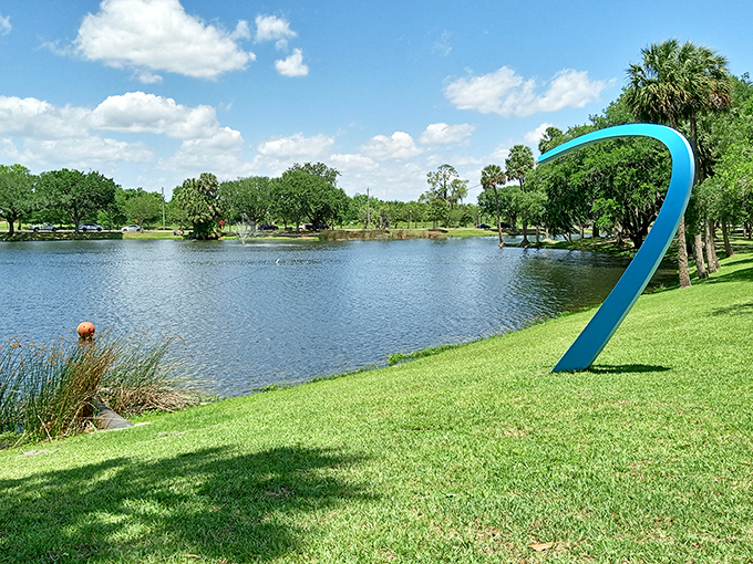 The sculptural blue curve at Tuscawilla Park creates an artistic counterpoint to nature's own masterpiece of still water and Florida sky.