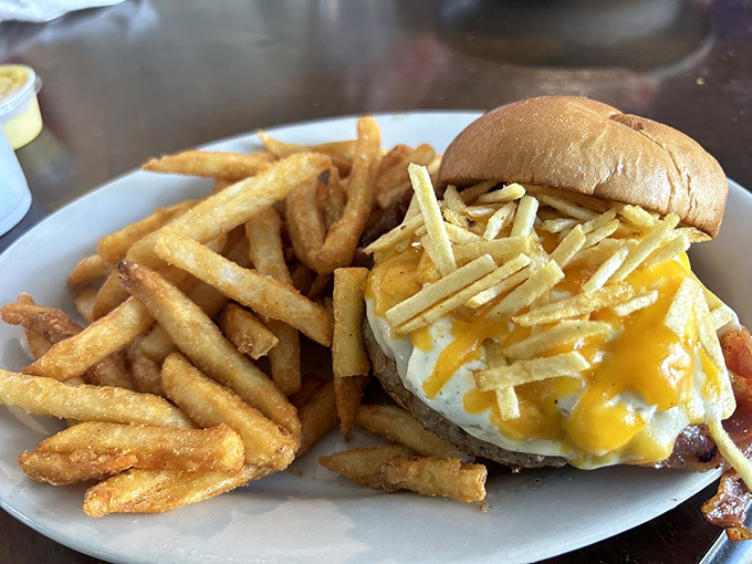 Golden fries flank a burger topped with a sunny-side-up egg. Breakfast and lunch having a delicious affair on one plate.