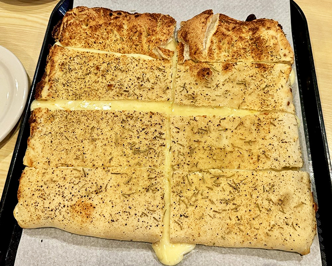 The white pizza glistens with herbs and cheese, a canvas of carbs where garlic and olive oil create a masterpiece that would make any Italian grandmother nod in approval.