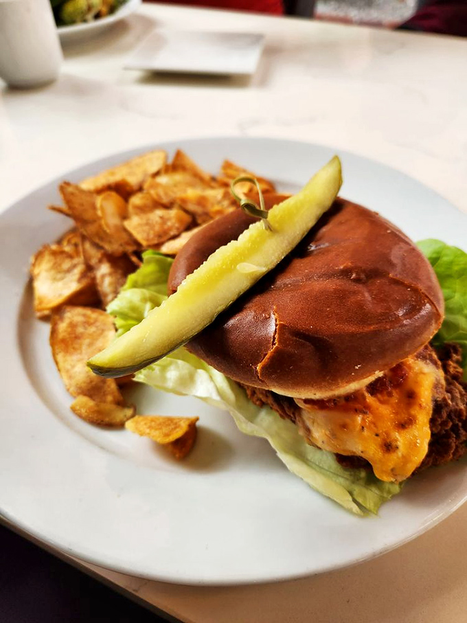 This isn't just a sandwich; it's architectural perfection with crispy chicken, fresh greens, and a pickle crown, all on a pillowy brioche throne.