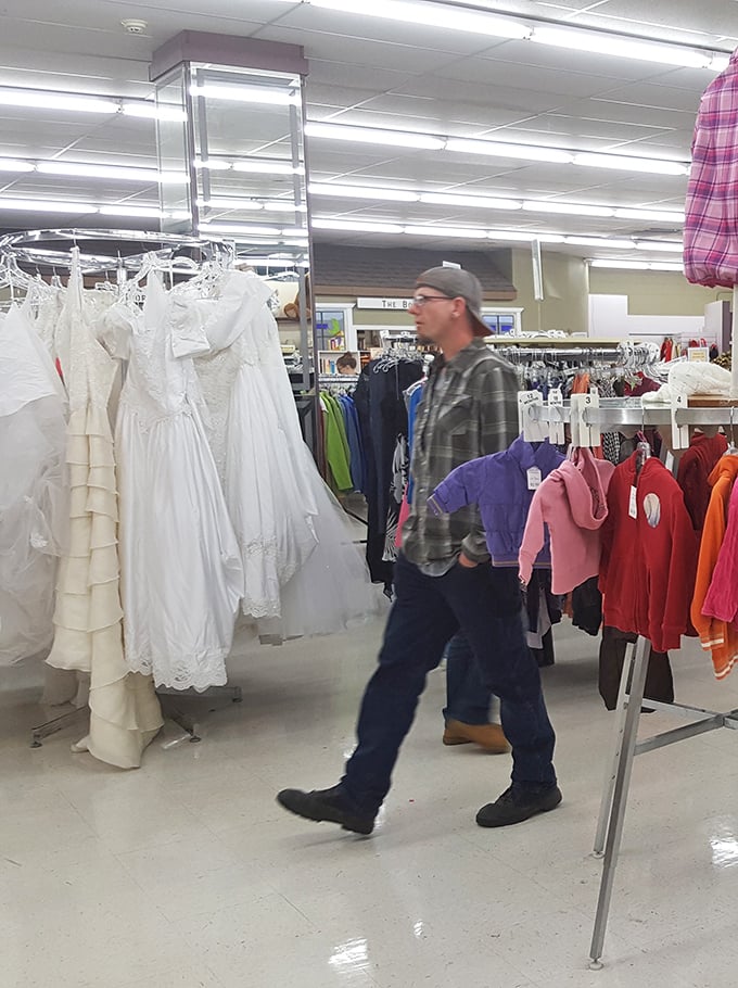A shopper browses wedding dresses that wait patiently for their second trip down the aisle, each with stories stitched into their seams.