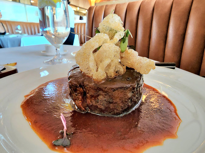 A filet mignon that's dressed better than most of us, wearing a crown of crispy onions and bathing in a sauce that demands to be sopped up.