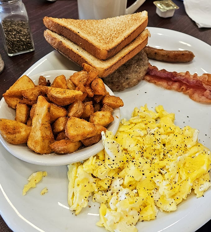 The breakfast trinity: perfectly scrambled eggs dusted with herbs, golden home fries, and toast ready for that essential morning butter bath.