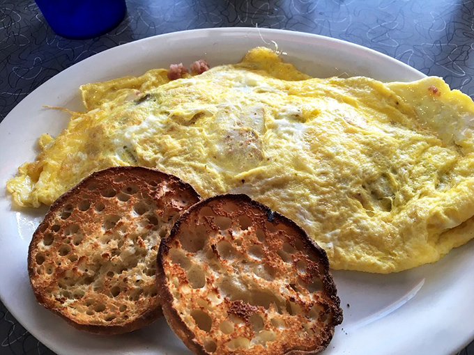 This omelet arrives like a yellow sunrise on your plate, promising to turn any ordinary morning into something special.