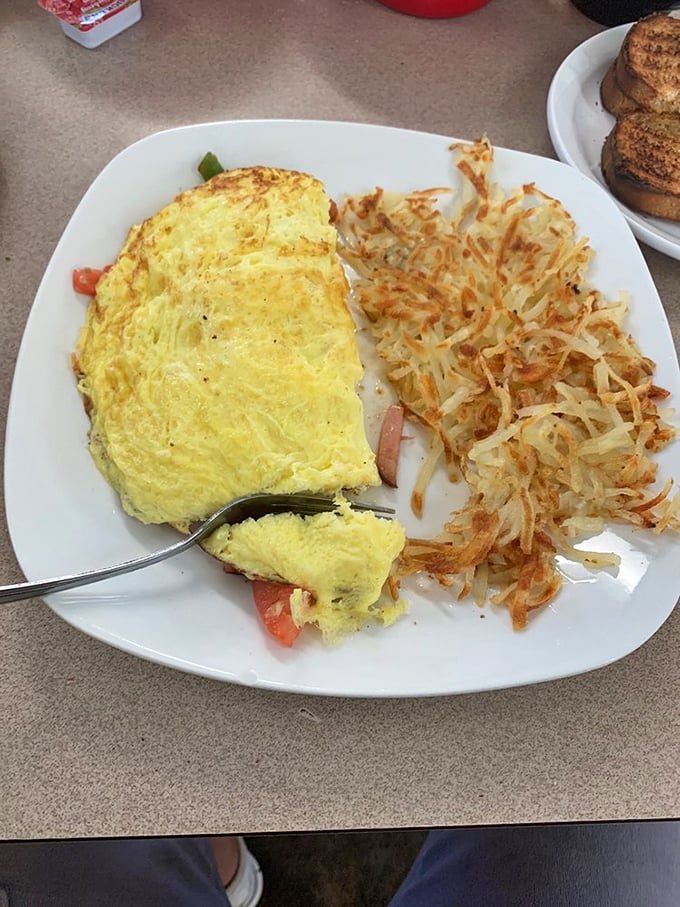 The omelet that launched a thousand sighs, sitting beside hash browns so perfectly crispy they practically play a symphony when your fork hits them.