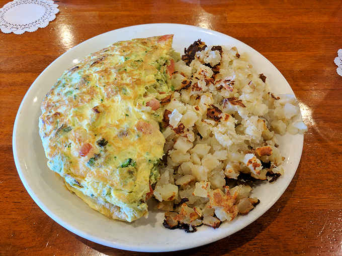 A fluffy omelet that's had a proper introduction to vegetables, nestled beside home fries with that ideal crisp-to-tender ratio.