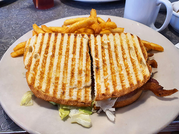 Perfectly grilled panini with crispy fries proves that lunch at a breakfast joint can be absolutely magnificent.