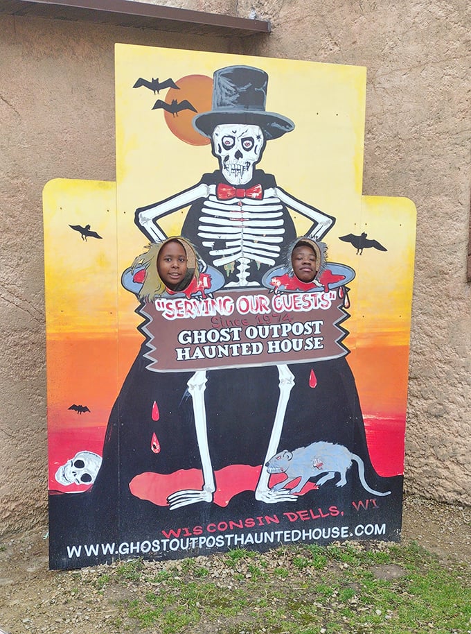 The Ghost Outpost Haunted House photo op invites brave souls to peek through. Those smiles suggest the scares inside might be delightfully tame.