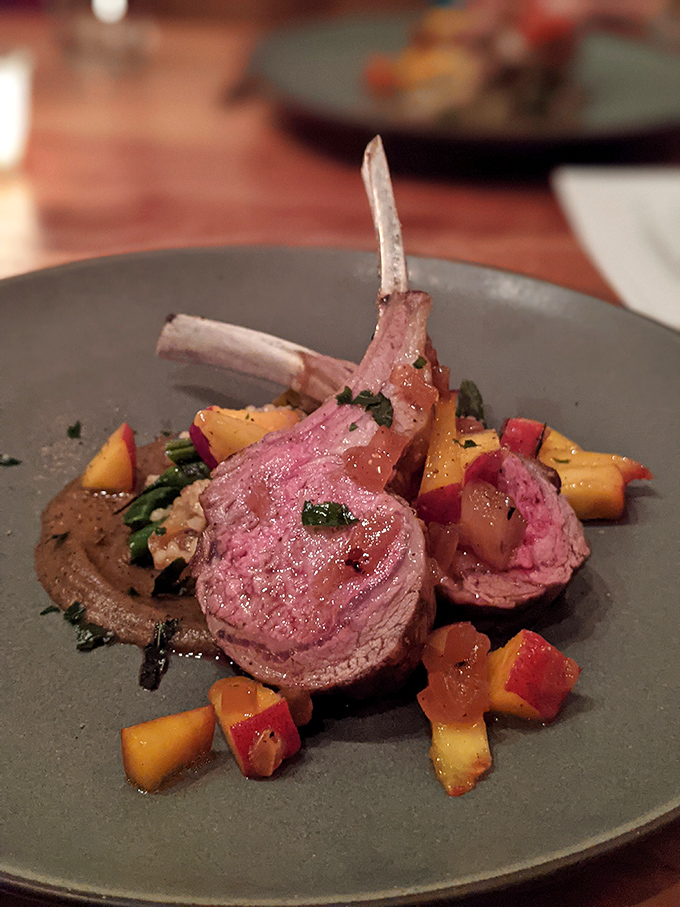 Lamb chops presented like the crown jewels they are. Pink, perfect, and positioned atop seasonal vegetables that aren't just garnish&mdash;they're part of the story.