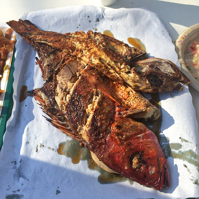 Whole grilled red snapper staring back at you, as if to say, "Yes, I'm delicious. Deal with it."