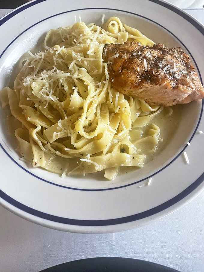 Perfectly seared salmon resting on a bed of fettuccine – proof that not all heroes wear capes, some wear chef coats.