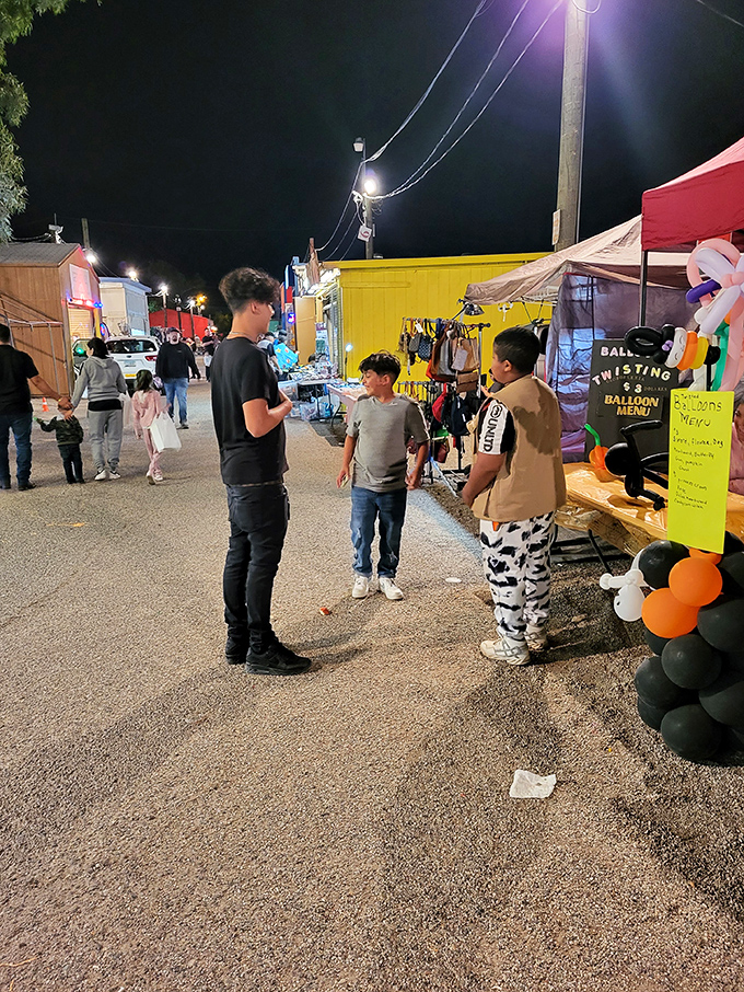 Young shoppers navigate the nighttime marketplace, where childhood wonder meets teenage independence amid the glow of string lights.