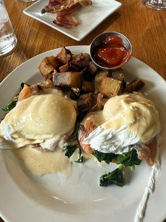 Benedict reimagined: Two perfectly poached eggs perched atop a bed of greens, with potatoes that have clearly been introduced to both butter and purpose.