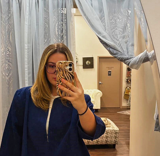 Elegant fitting areas with flowing curtains create a boutique experience. Your reflection doesn't know these clothes had previous owners.