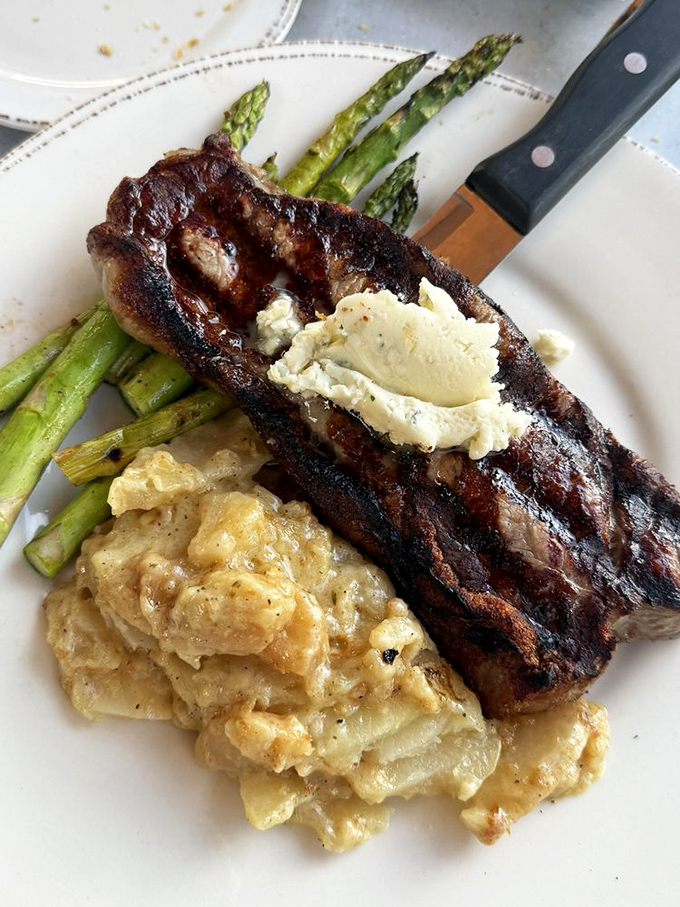 Surf meets turf in perfect harmony: a perfectly grilled steak topped with herb butter, flanked by asparagus soldiers standing at attention.