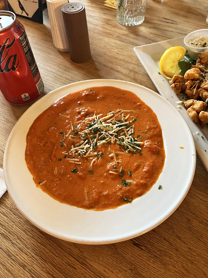 A bowl of tomato soup that glows with promise, topped with cheese that's slowly melting into the warm embrace below.