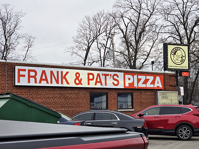 Cranky Pat's bold red sign cuts through winter snow like a promise &ndash; great pizza waits, regardless of Wisconsin weather!