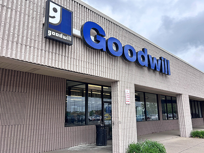 Goodwill's bold blue signage stands out against textured concrete. Behind those doors, secondhand becomes second chance.