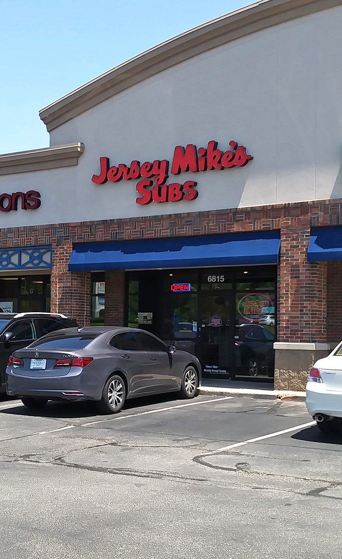 Jersey Mike's bright signage cuts through parking lot monotony like a freshly sharpened slicer through premium deli meats.