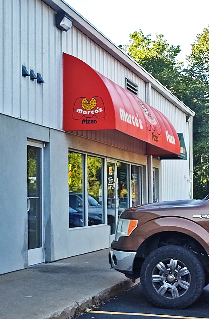 Marco's bright red awning signals pizza paradise ahead. Like a lighthouse guiding hungry sailors to cheesy, saucy shores.