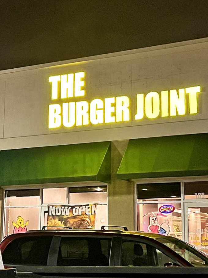 The Burger Joint's illuminated sign glows like a beacon for hungry night owls. Those cartoon characters in the window add a playful touch.