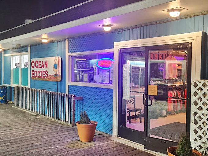 The blue-sided Ocean Eddie's glows with neon promise at dusk &ndash; a beacon for hungry beachgoers seeking seafood salvation.