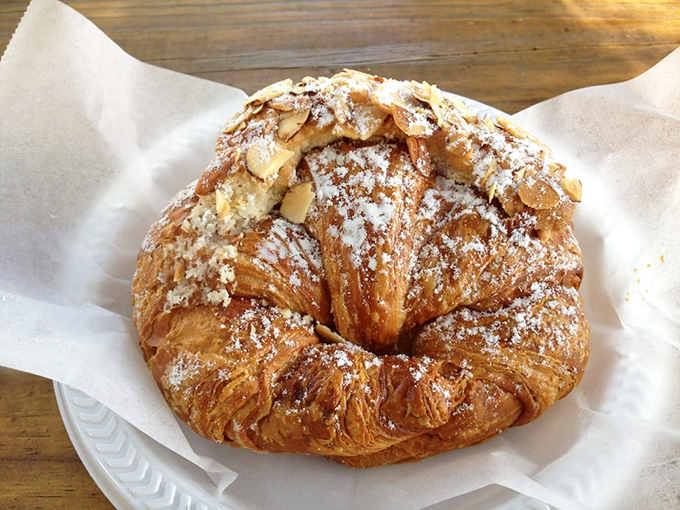 Golden almond croissant dusted with powdered sugar - flaky pastry perfection that melts upon first bite.