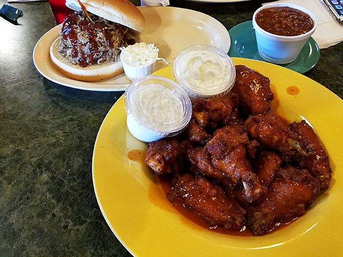 Wings and a sandwich sharing table space like old friends. That sauce isn't just coating the chicken&mdash;it's transforming it into something worth crossing state lines for.