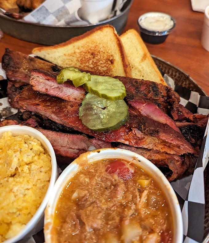 Ribs displaying that perfect "kiss of smoke" complexion, with sides standing by for moral support. That pickle isn't decoration&mdash;it's a palate-cleansing necessity.