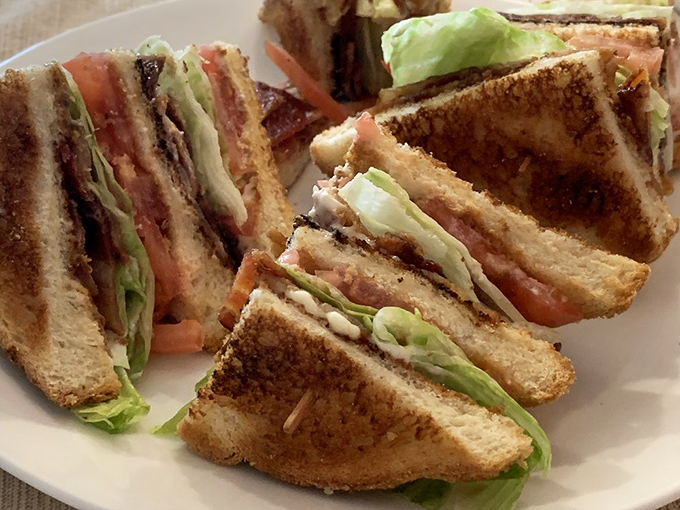 The humble club sandwich, elevated to art form. Crispy bacon, fresh lettuce, and toasted bread&mdash;the holy trinity of lunchtime satisfaction.